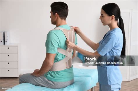 환자가 클리닉에서 자세 교정기를 착용하도록 돕는 정형 외과 의사 척추측만증 치료 Kyphosis에 대한 스톡 사진 및 기타