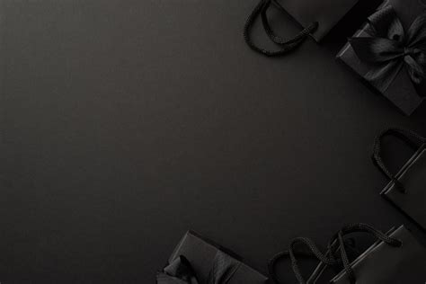 블랙 프라이데이 판매 개념 카피 스페이스가있는 고립 된 검은 배경에 리본 활과 종이 봉지가있는 검은 선물 상자의 상단보기 사진