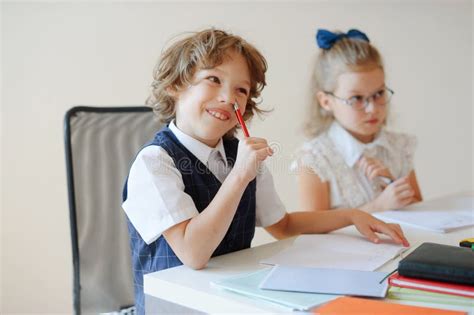 Los Pequeños Alumnos Divertidos Se Sientan En Un Escritorio Imagen De