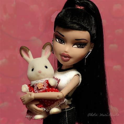 A Close Up Of A Doll Holding A Stuffed Animal In Her Arms With A Pink