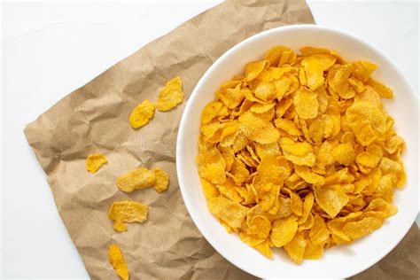 Breakfast Cereal Concept Cornflakes In Bowl And Cornflakes Fragments Falling On Brown Paper
