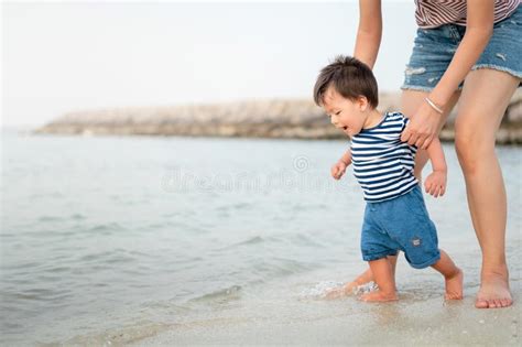 Baby Boy Making His First Steps On The Beach With His Mother Stock