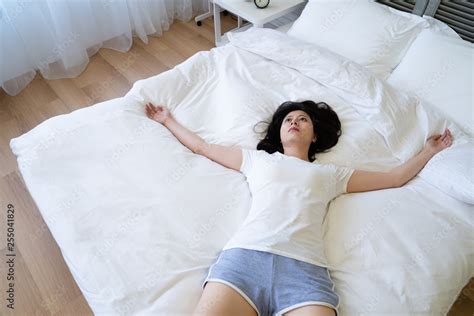 Top View Depressed Korean Woman Lying On Bed With Arms Outstretched