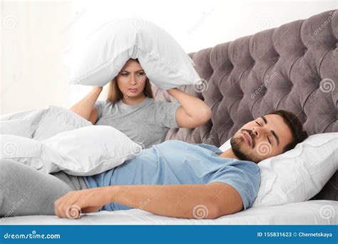 Upset Young Woman Sitting On Bed Her Sleeping Husband At Home