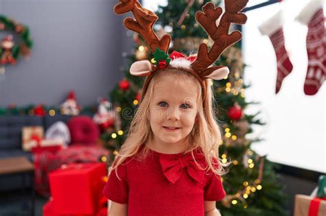 Adorable Blonde Girl Smiling Confident Standing By Christmas Tree At