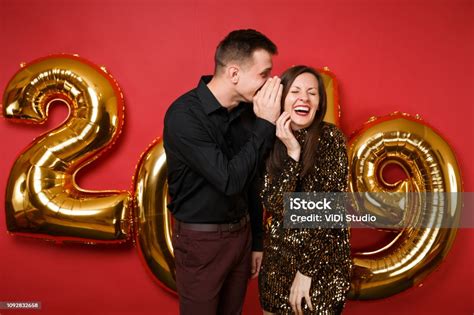 반짝 반짝에 커플 남자 여자 드레스 밝은 빨간 벽 배경 황금 번호 공기 풍선 스튜디오 초상화에 고립 된 크리스마스 파티를 축 하 하는 검은 셔츠 행복 한 새 해 2019