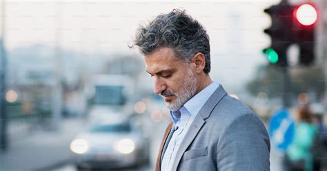 도시에서 스마트폰을 들고 문자 메시지를 보내는 잘생긴 성숙한 사업가 사진 Unsplash의 자동차 이미지