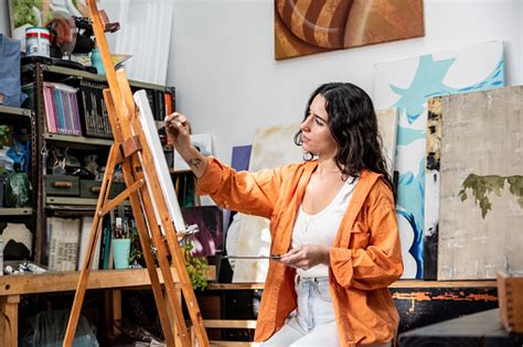 집에서 예술가의 팔레트를 들고 있는 동안 캔버스에 그림을 그리는 중년 여성 30 34세에 대한 스톡 사진 및 기타 이미지 30 34세 곱슬 머리 그리기 Istock