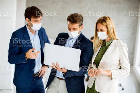 젊은 이들이 그들 뒤에 작동 사무실에서 실내에서 손에 노트북을 들고 서 두 남자와 여자 3 명에 대한 스톡 사진 및 기타 이미지