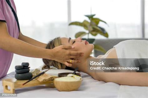 뷰티 스파에서 얼굴 마사지를 받는 아름다운 아시아 여성 머리를 마사지하면서 실내 스파에서 휴식을 취하는 눈을 감은 젊은 여자