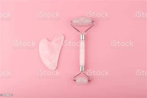 분홍색 배경에 핑크 석영으로 만든 비취 롤러와 하트 모양의 마사지기의 최고 보기 과샤 마사지 컨셉 0명에 대한 스톡 사진 및