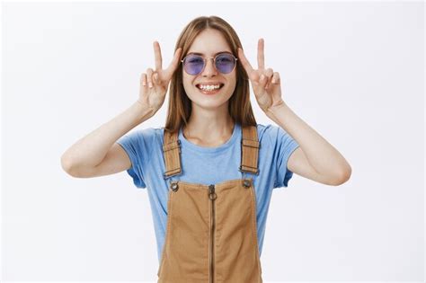 Optimistisches glückliches attraktives mädchen das friedensgeste zeigt