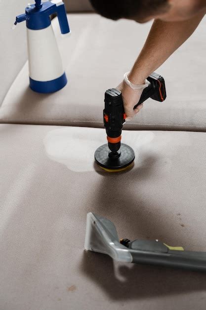 Untar detergente en el sofá usando un taladro con cepillo para limpieza