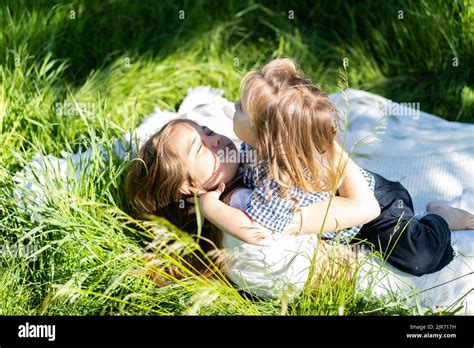 Brother And Sister Are Playing In The Park Among The Green Grass