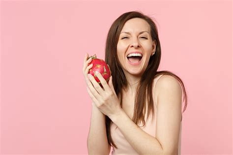 신선한 잘 익은 피타 하 야를 들고 가벼운 옷에 쾌활 한 젊은 여자 스튜디오에서 분홍색 파스텔 벽 배경에 고립 된 드래곤 과일 사람들은 생생한 라이프 스타일 휴식 휴가