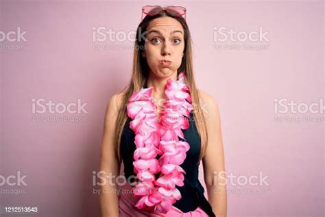 젊은 아름 다운 금발 여자 수영복을 입고 꽃 하와이 안 레이 핑크 배경 퍼핑 뺨 재미 있는 얼굴 공기 미친 표정으로 입이 팽창