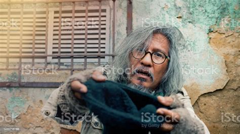 더러운 옷을 입은 노숙자는 불쌍한 눈으로 음식과 돈을 요구하는 행인들의 도움을 청하고 있습니다 도움의 필요성을 표현하는 얼굴 집이 없으며 길가에서 자고 있습니다 60 64