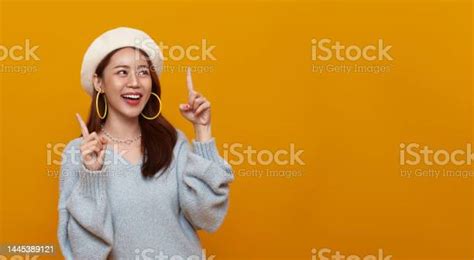 아름 다운 젊은 아시아 여자는 복사 공간을 가리키고 노란색 배경에 고립 된 미소 짓는 얼굴 텍스트 광고를 위한 빈 공간을 보고