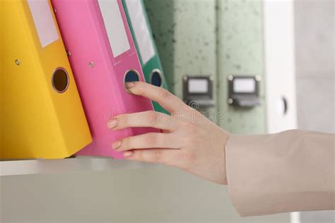 Woman Taking Folder With Documents From Shelf In Office Closeup Stock
