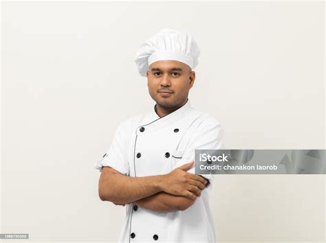 미소 짓는 젊은 잘 생긴 아시아 남자 요리사가 유니폼을 입고 모자를 쓰고 고립 된 흰색 배경에 카메라를 보며 게시합니다 요리 남자 직업 요리사 또는 빵집 부엌 레스토랑과