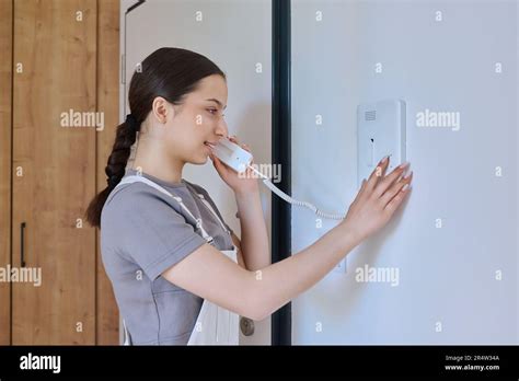 Teenage Girl Holding Intercom Handset While Talking To Guest Stock Photo Alamy