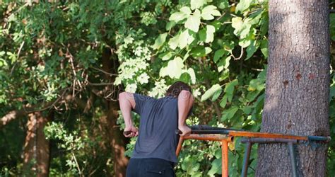 Man Approaches Uneven Bars For Doing Exercises In City Garden Stock