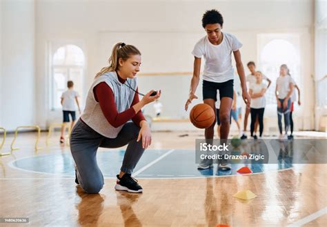 Young Female Coach Using Stopwatch During Physical Activity Class With
