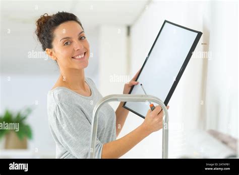 Woman Positioning Picture Frame On Wall Stock Photo Alamy
