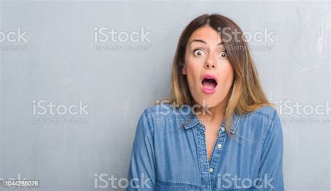 그런 지 회색 벽 입고 데님 의상 두려워 하 고 놀라운 식으로 충격을 통해 젊은 성인 여자는 공포 하 고 얼굴을 흥분 갈색