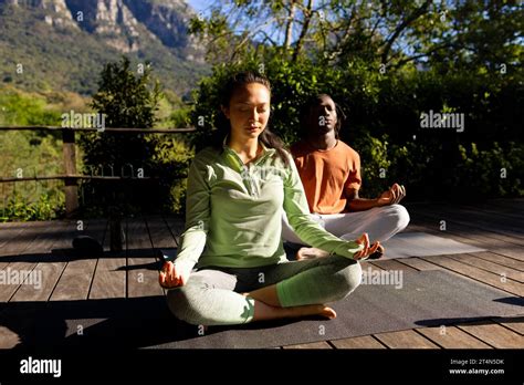Happy Diverse Couple Practicing Yoga Meditation Sitting On Deck In