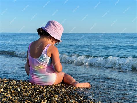 Una Chica En Traje De Baño Y Sombrero Panamá Está Sentada En Una Playa