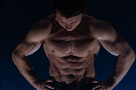 Homem musculoso mostrando músculos isolados no fundo preto estilo de