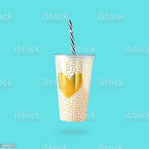 Minimalism 개념입니다 골드 하트 장식 소 다 또는 빨 대를 마시는 차가운 음료와 함께 흰색 플라스틱 컵 금 금속에 대한