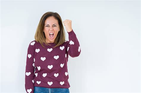 고립 된 배경 위에 심장 스웨터를 입고 아름 다운 중간 나이 여자 화가 분노를 제기 주먹 좌절 하 고 화가와 함께 외치는 동안 분노 분노와 공격적인 개념 갈색 머리에 대한