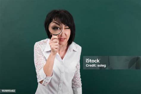 여 자가 보이는 돋보기 배경으로 칠판을 통해 앞으로 큰 눈은 돋보기 교육 및 비즈니스의 개념 안에 표시 개념에 대한 스톡 사진