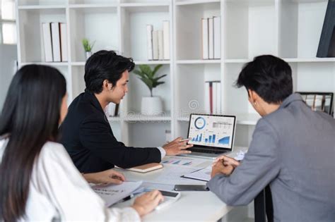 Business Team Collaborating In Modern Office Analyzing Data On Laptop And Sharing Ideas For