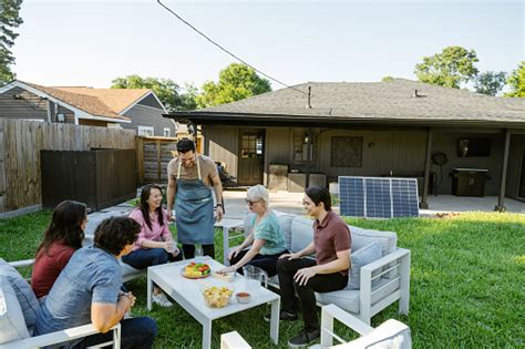 뒤뜰에 모여 바베큐를 즐기는 다세대 가족 뒷마당에 태양 전지판이 설치된 현대적인 중산층 주택이 있는 라틴 가족 30 39세에 대한 스톡 사진 및 기타 이미지 Istock