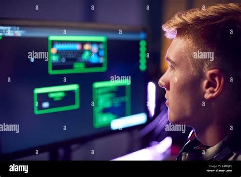 Male Teenage Hacker Sitting In Front Of Computer Screens Bypassing