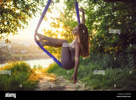 A Young Female Gymnast Is Engaged In Aerial Yoga Using A Combination