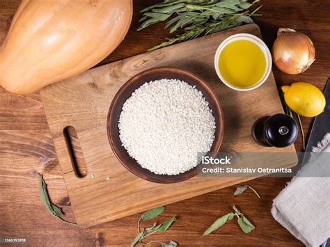 호박 리조또 요리 재료 호박 접시에 쌀 올리브 오일 양파와 나무 도마에 양파와 레몬과 세이지의 무리 최고 전망 가을에 대한 스톡