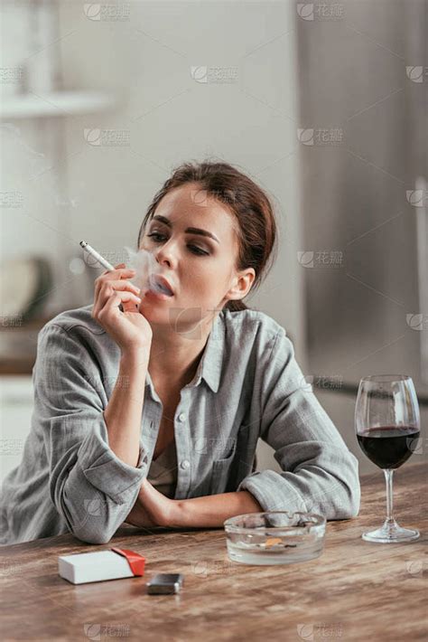 在餐桌上的酒杯边抽烟的女人