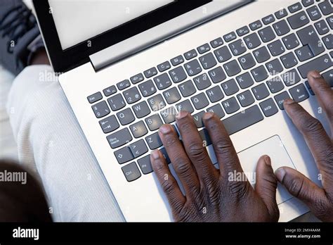 Close Up African Black Hands Typing On Laptop Computer Keyboard On Legs