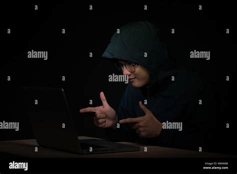 Successful Male Hacker Poses In Front Of Laptop Computer Clenches Fists Dressed In Black