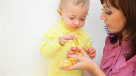 Young Mother And Her Little Daughter Eating Orange Stock Footage