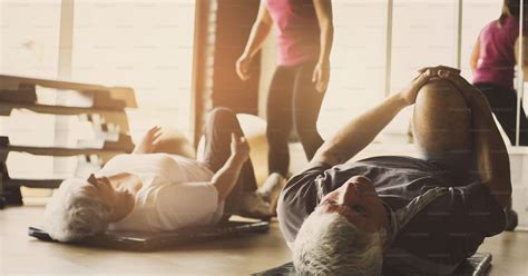 재활 센터에서 노부부 운동 개인 트레이너는 노인 부부가 바닥에서 스트레칭을 할 수 있도록 도와줍니다 N 사진