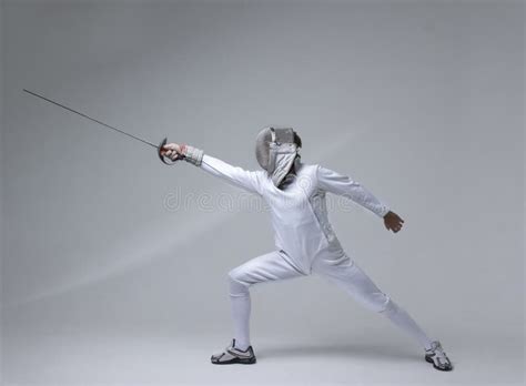 Professional Fencer In Fencing Mask Attacking On Grey Background Stock