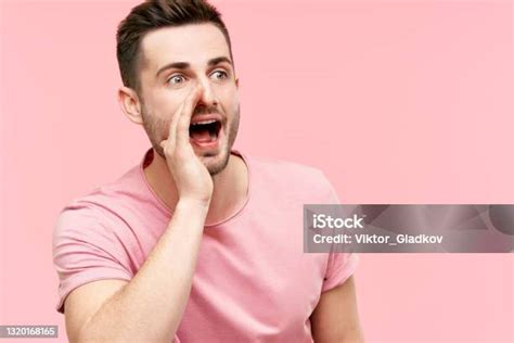 젊은 잘 생긴 남자 소리와 입에 손으로 옆으로 큰 소리로 비명을 지르고 분홍색 배경에 텍스트 공간을 복사 25 29세에 대한 스톡 사진 및 기타 이미지 Istock