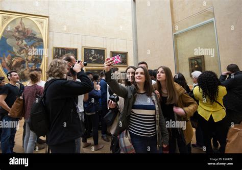 Tourists Taking A Selfie In Front Of The Mona Lisa At The Louvre Museum