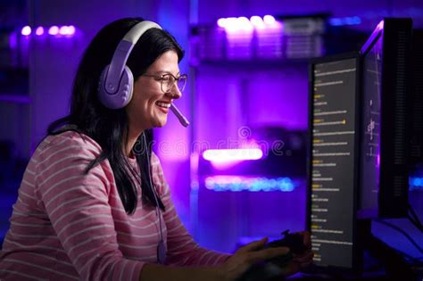Low Key Lighting Shot Of Female Gamer In Front Of Computer Screens With