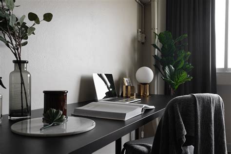 노트북 흰색 촛불 및 배경 아파트 인테리어 복사 공간에 베이지 색 페인트 벽이있는 검은 나무 작업 테이블에 유리 화병에 인공 식물로 장식 된 침실 작업 코너 단일 이미지에